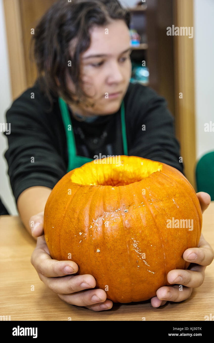 Teenager is carving jack-o-lantern. Helloween time. Holiday symbol ...