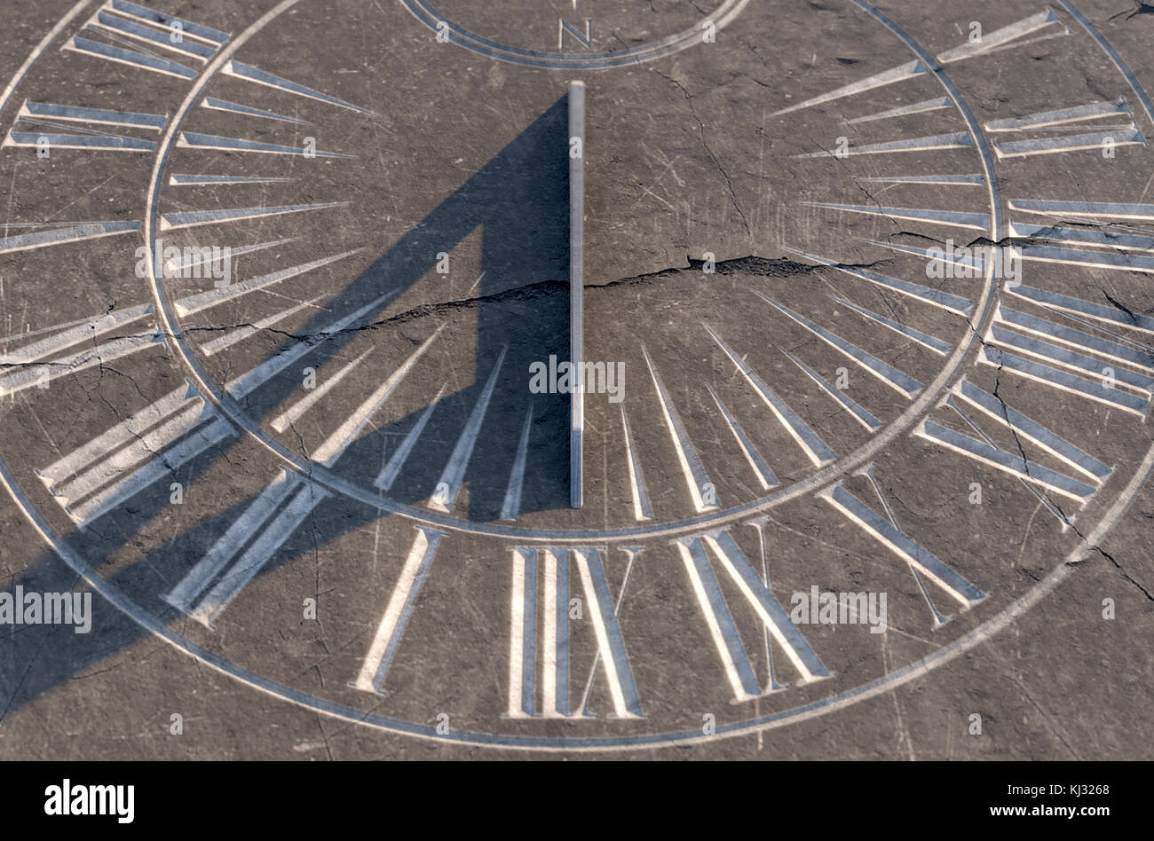An old stone sundial with etched roman numerals standing an a ...