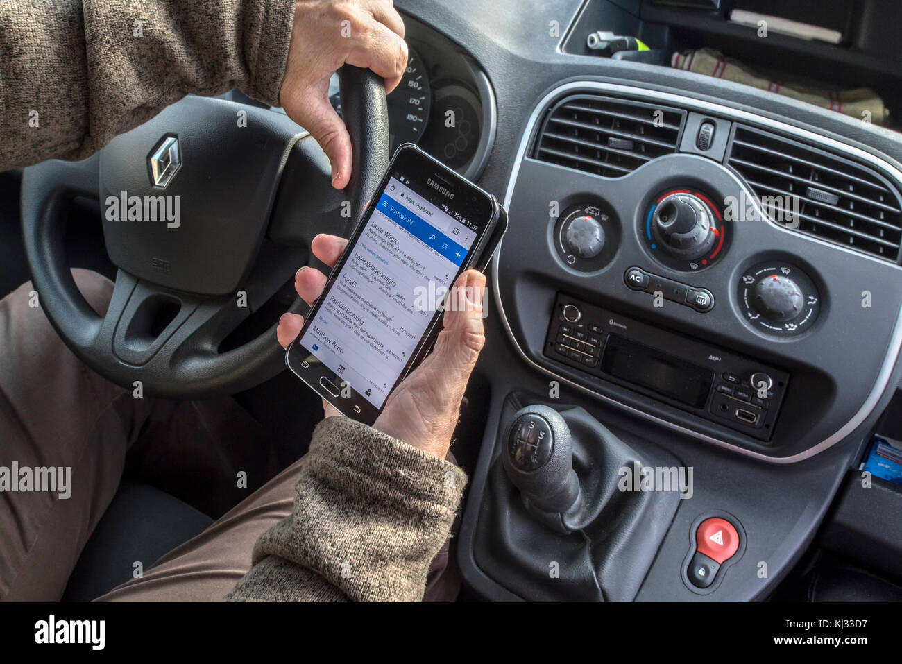 Irresponsible man at steering wheel checking messages on smart phone ...