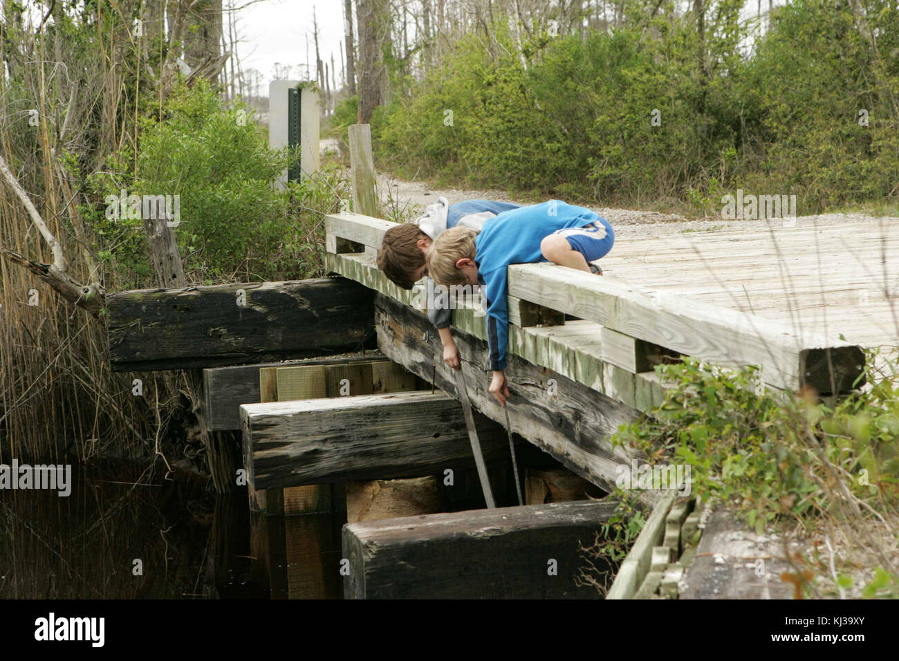 Two boys play on the bridge with long sticks Stock Photo - Alamy