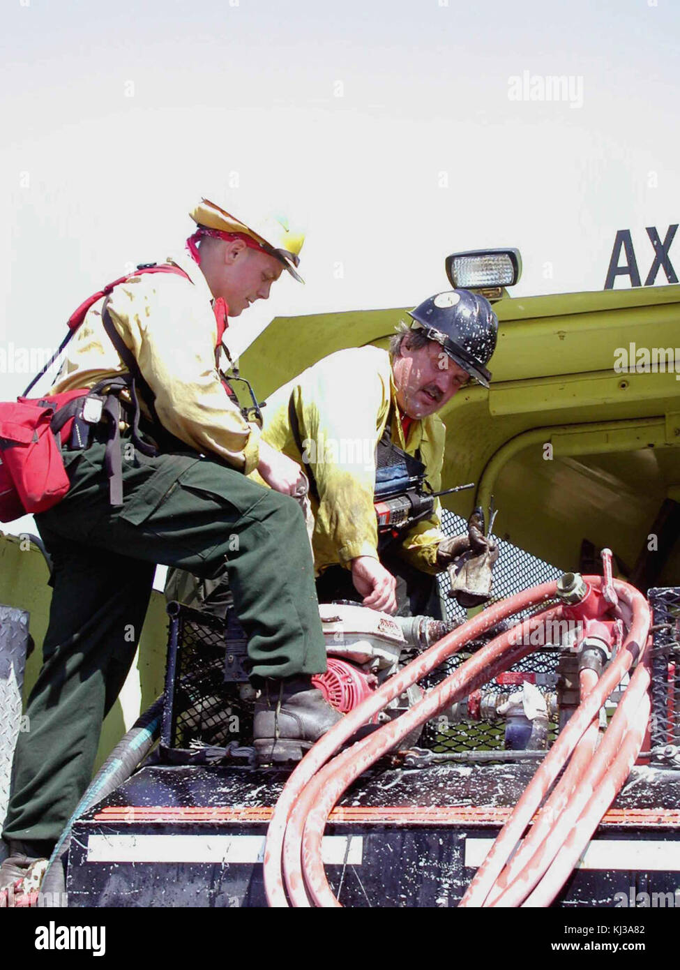Two firemans repairing fire engine pump on huse truck Stock Photo - Alamy