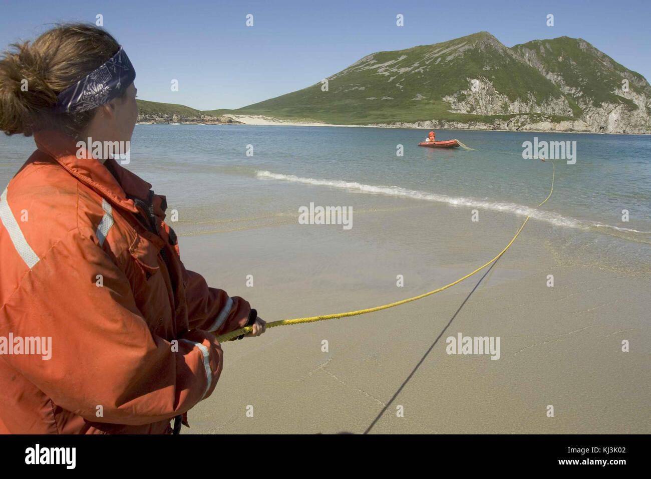 Woman standing on the shore and pulling out boat from water to the ...