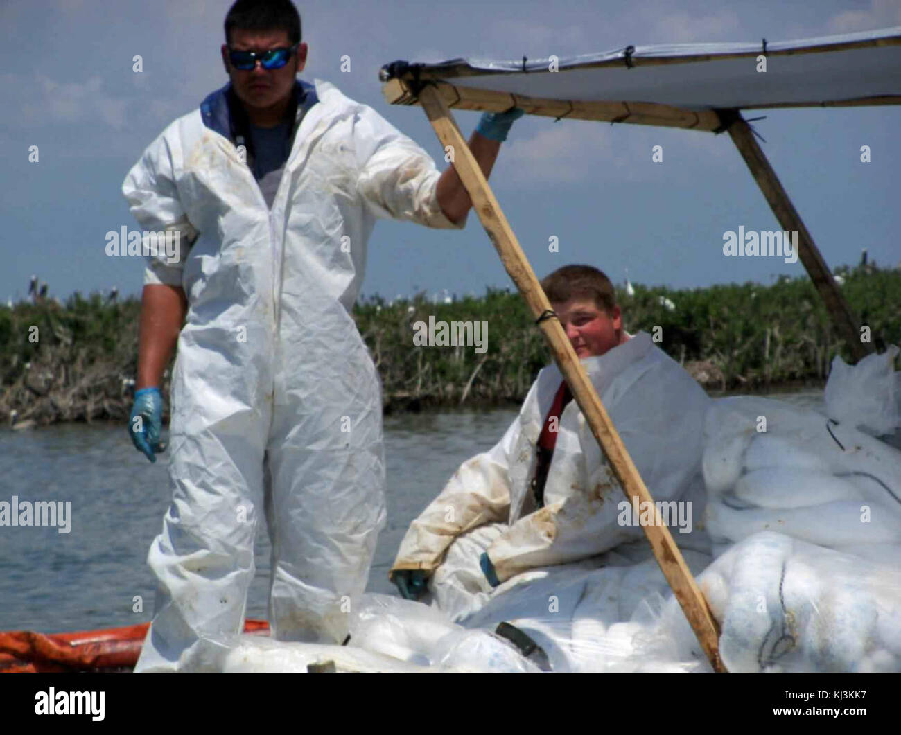 Workers on boat in white suits Stock Photo - Alamy