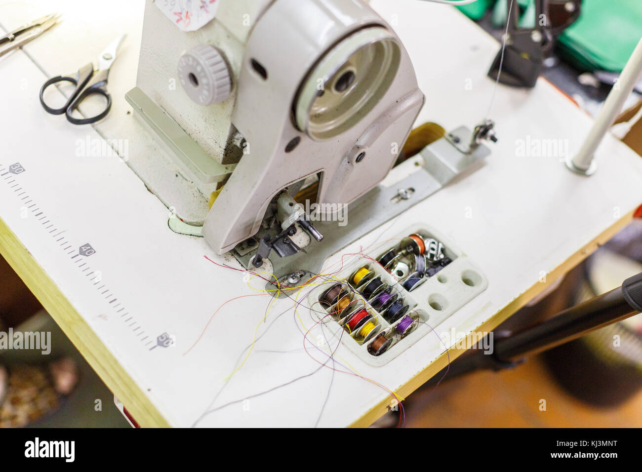 close-up of the sewing machine with multicolored threads and scissors ...