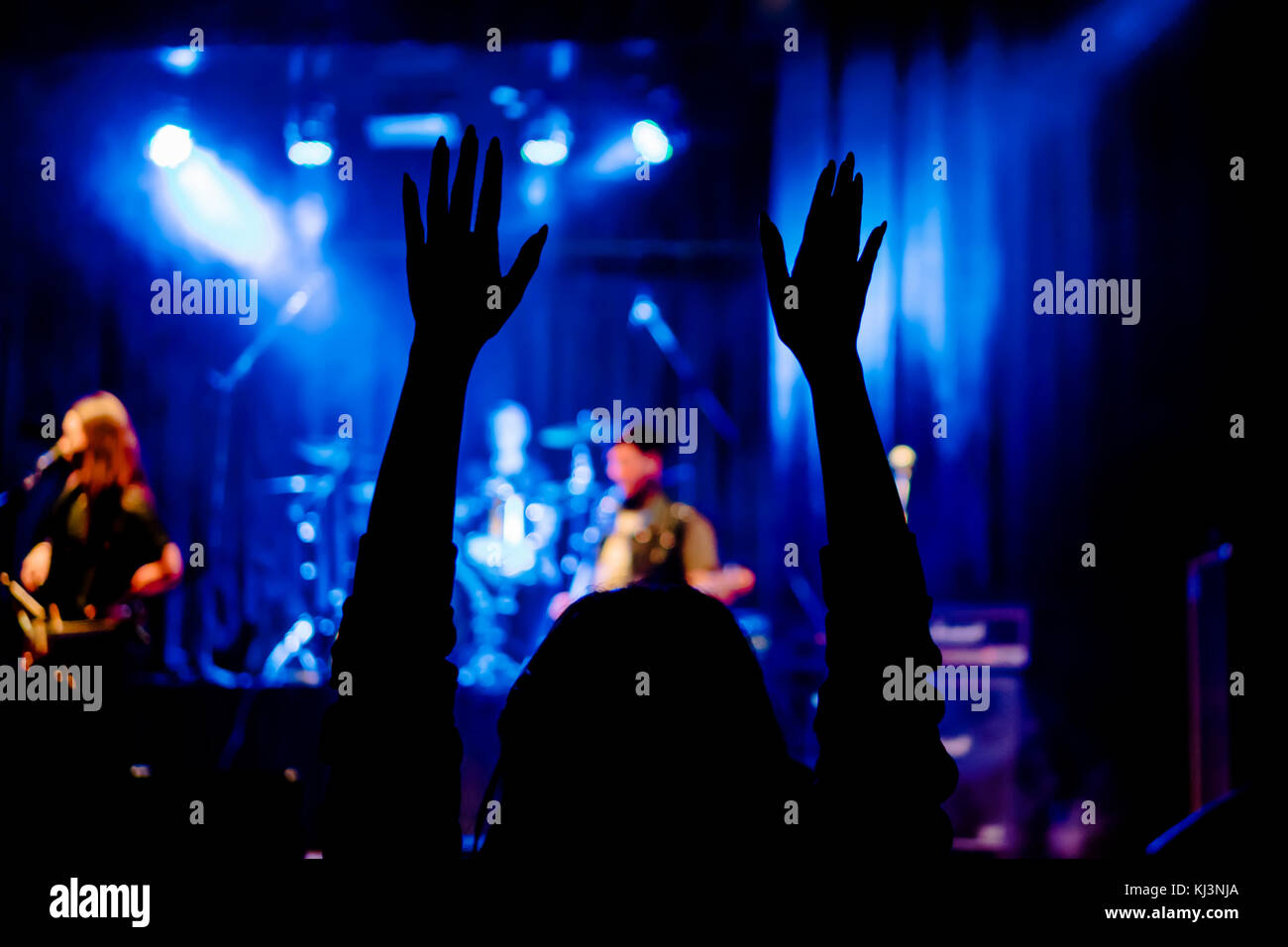 Silhouette of female hands raised at a rock concert in front of the ...