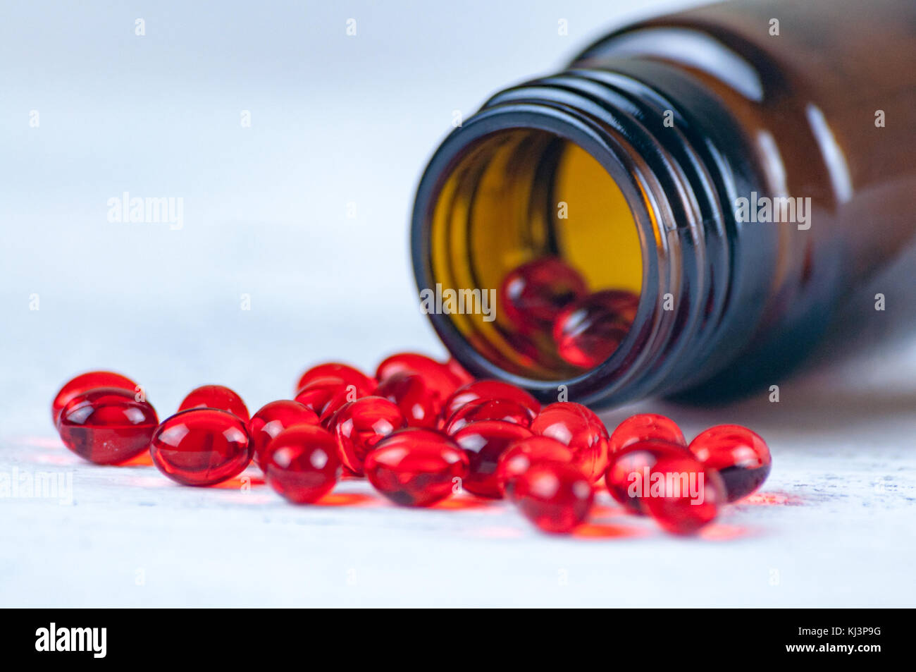Red capsules with medicine or vitamins in liquid form lie on a white ...