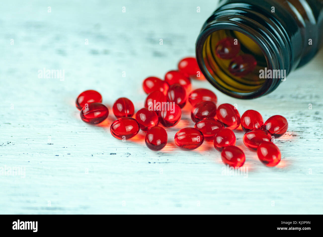 Red capsules with medicine or vitamins in liquid form lie on a white ...