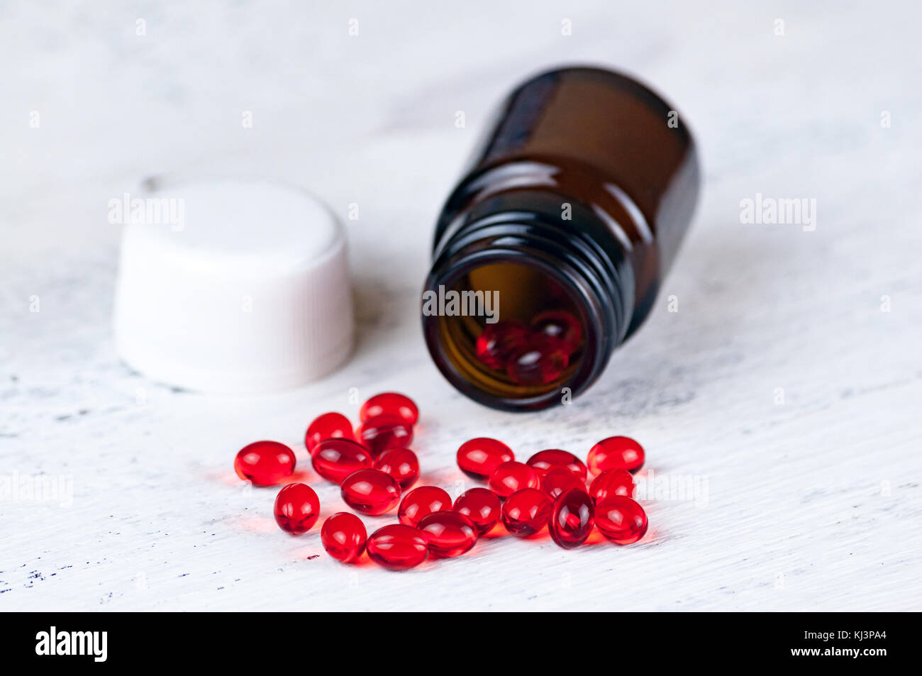 Red capsules with medicine or vitamins in liquid form lie on a white ...