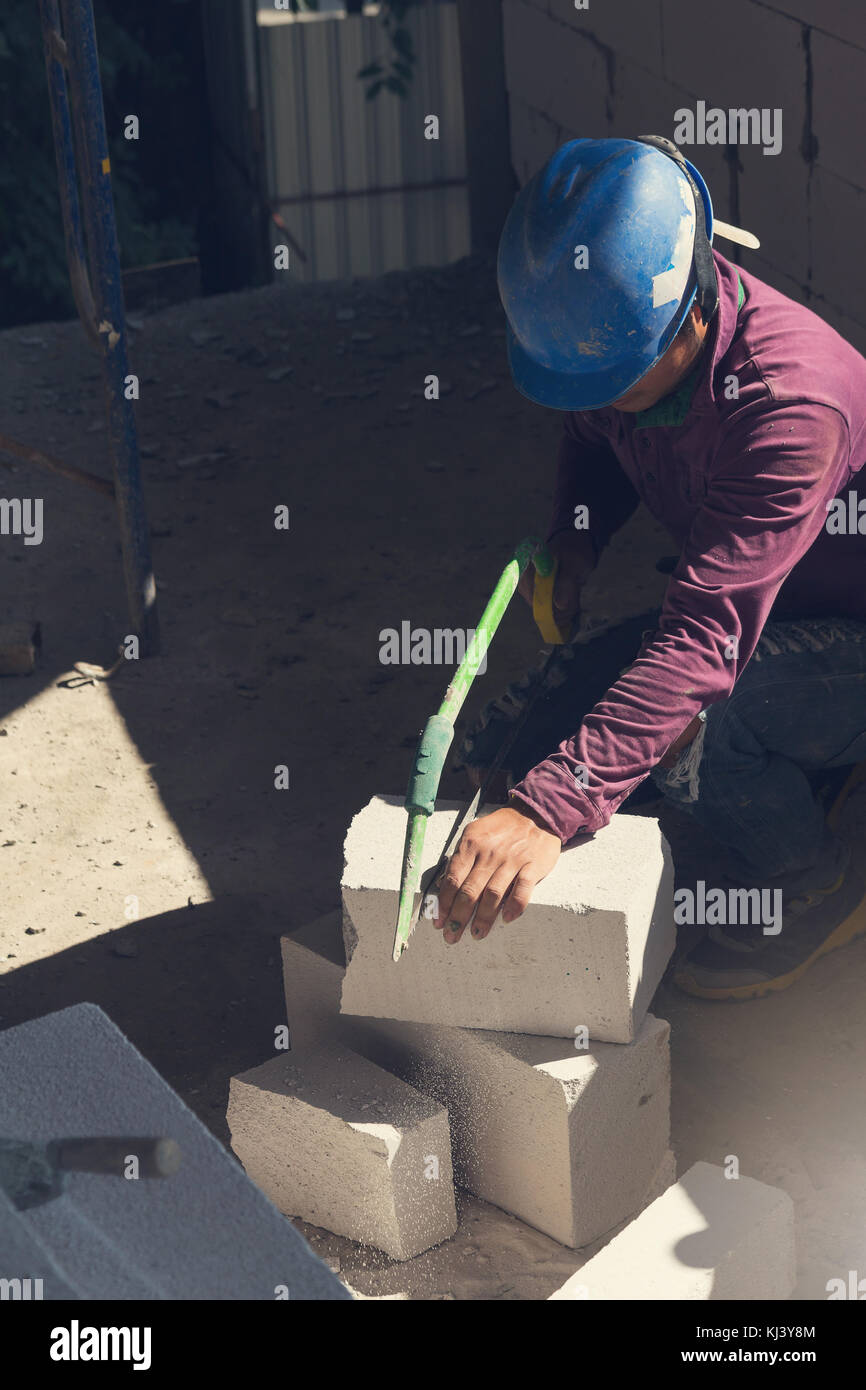 Construction concept, Bricklayer worker installing wite blocks to build ...