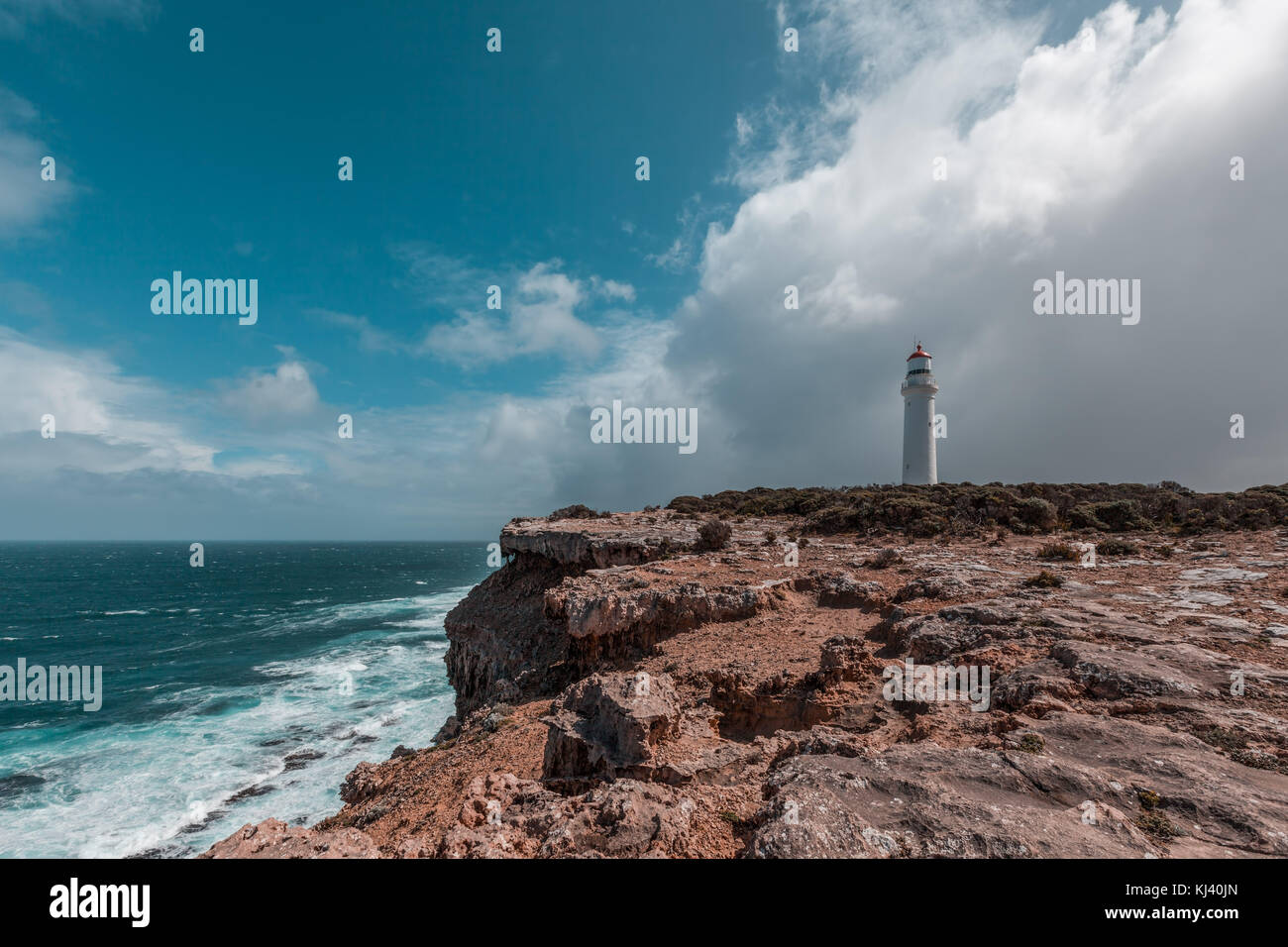 Cape Nelson lighthouse standing on a rugged cliff above ocean under ...