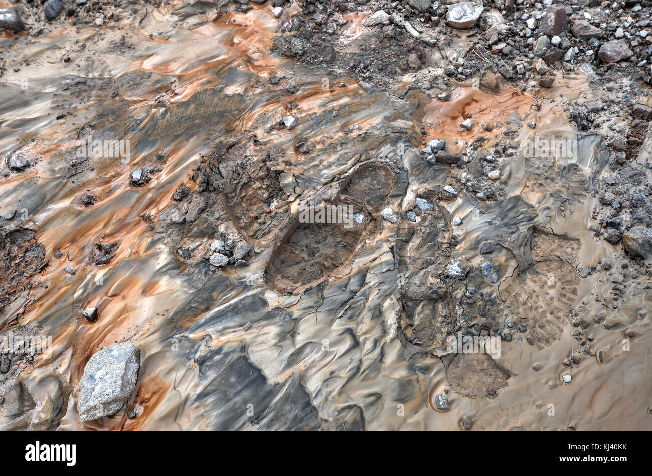 A boot print in the mud of a mining operation. Oxidized residue from ...