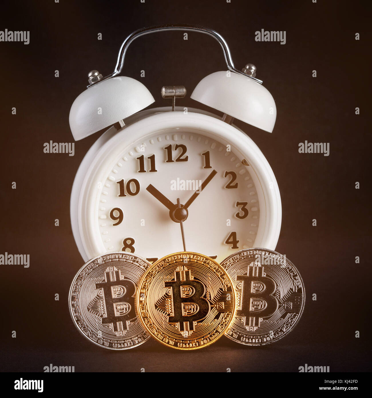 Three bitcoins and vintage white alarm clock glowing on black ...