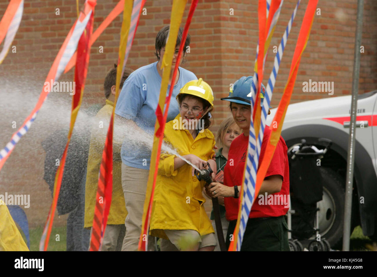 A photograph capturing a young girl extinguishing a fire on a wall. The ...