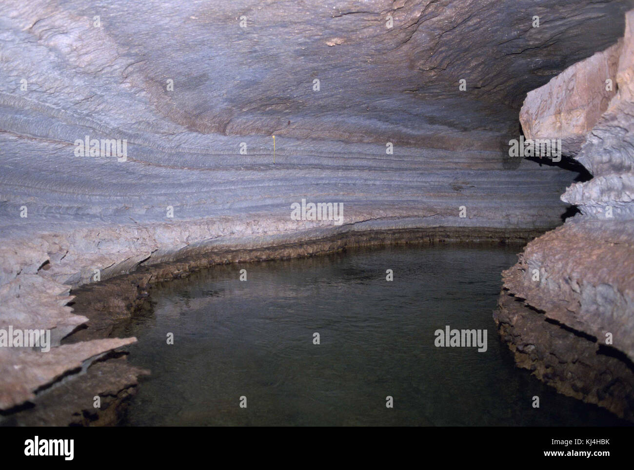 Cave interior waterway with arched ceiling and flowing water in channel ...