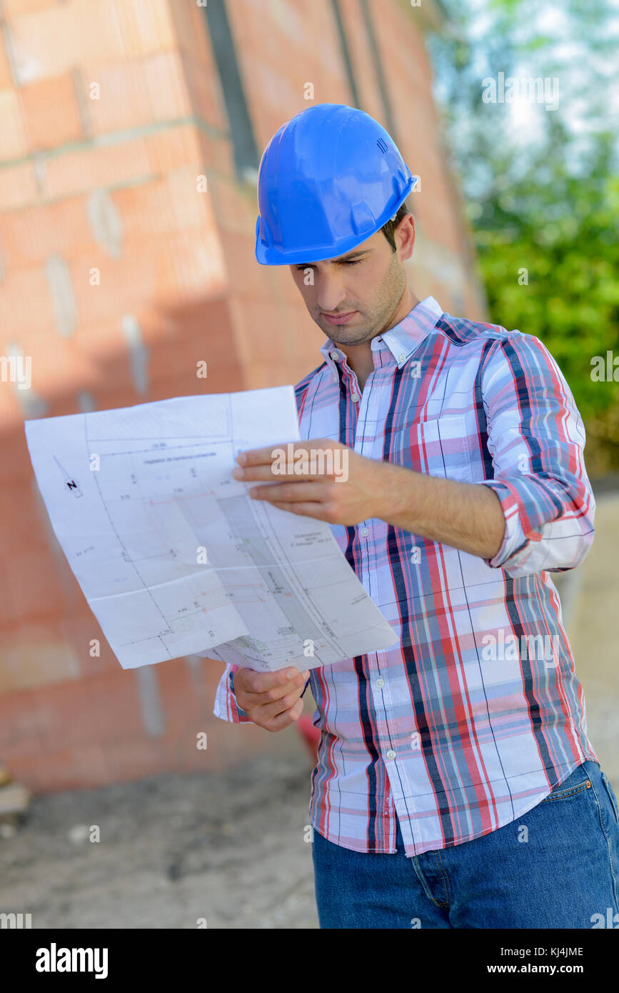 Architect reading blueprints on site Stock Photo - Alamy