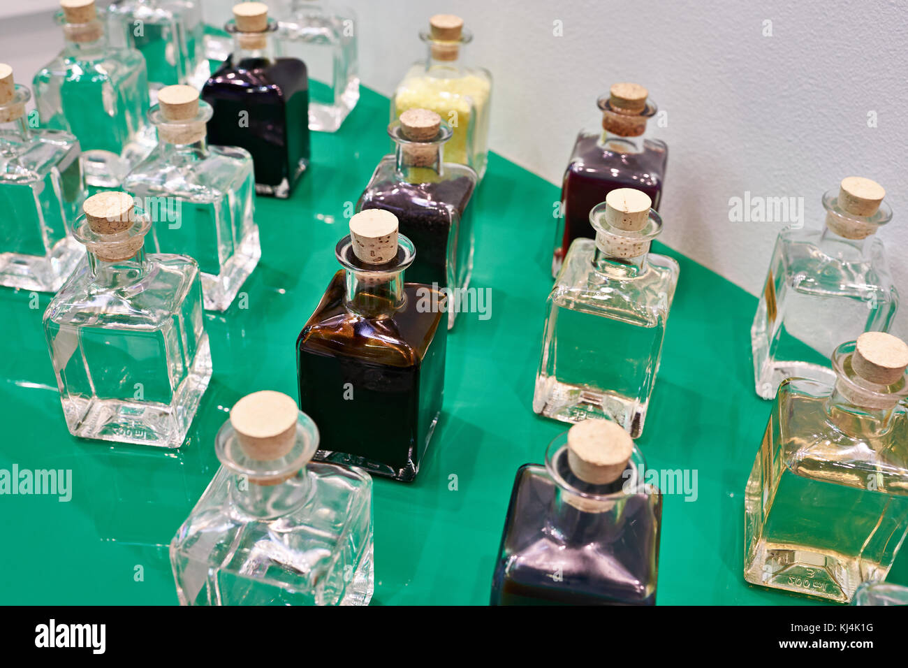 Square bottles with different chemical liquids on green background ...