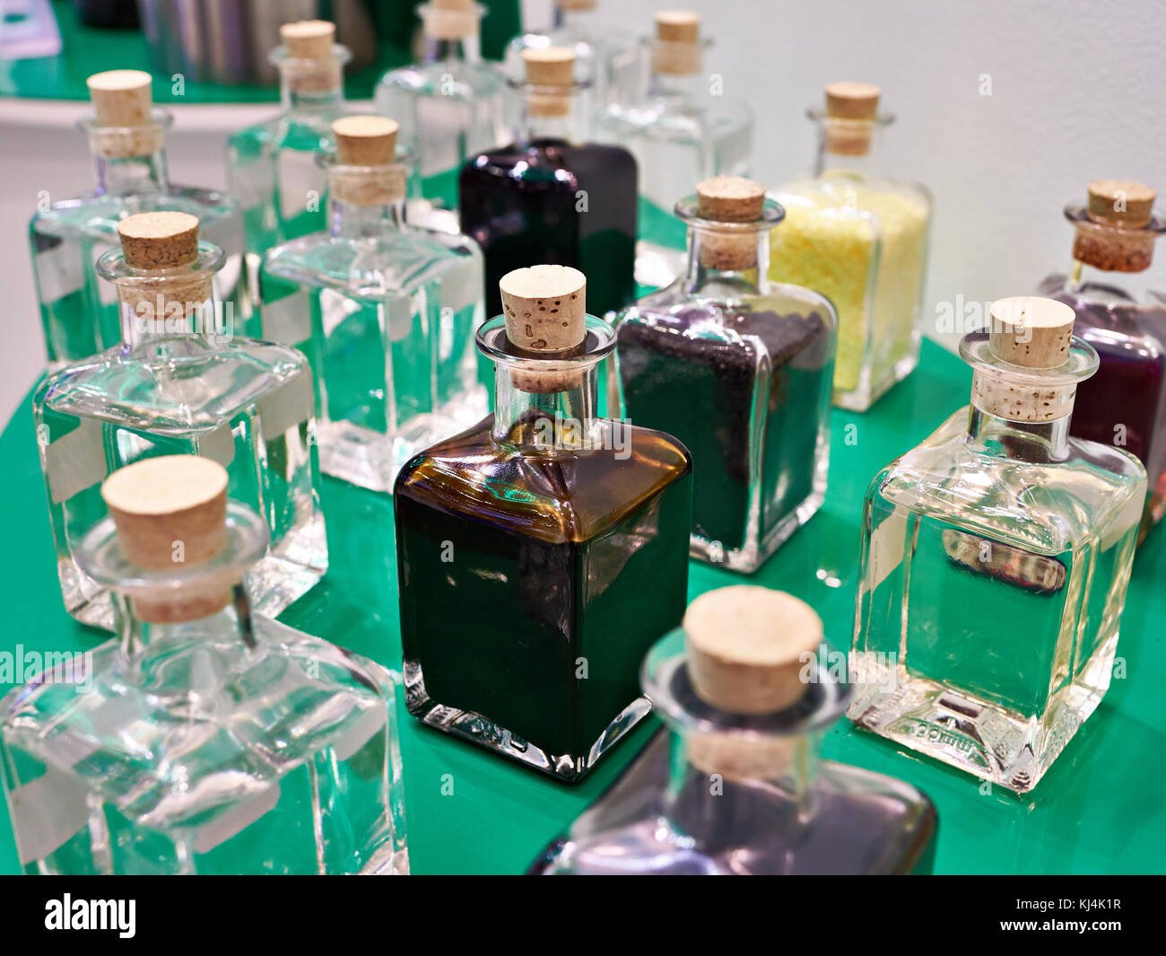 Square bottles with different chemical liquids on green background ...