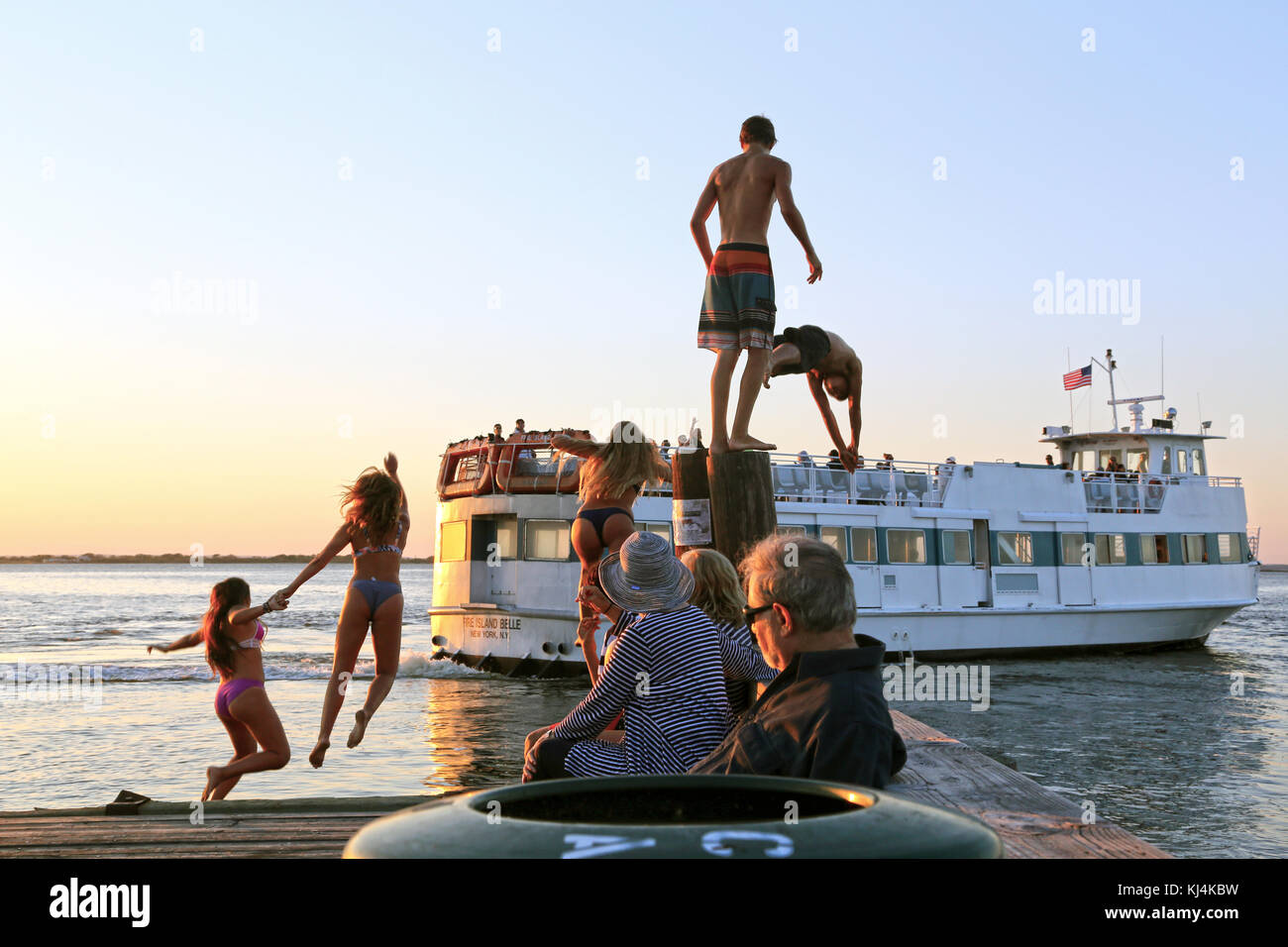Teens jumping off dock at dusk, Fair Harbor, Fire Island, NY, USA Stock ...