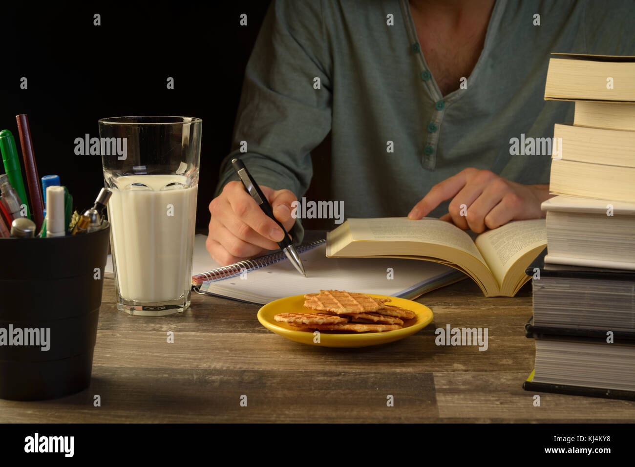 young man sitting at a study table desk with books a open sketch book ...