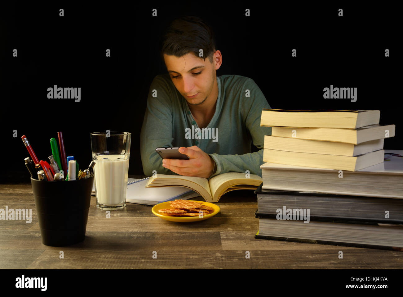 young man sitting at a study table desk with books a open sketch book ...