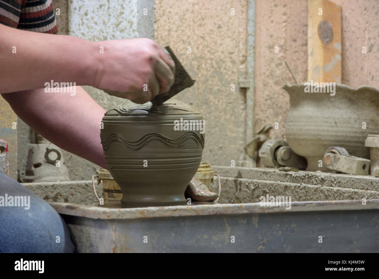 Man potter at work creating some traditional cups of white clay ...