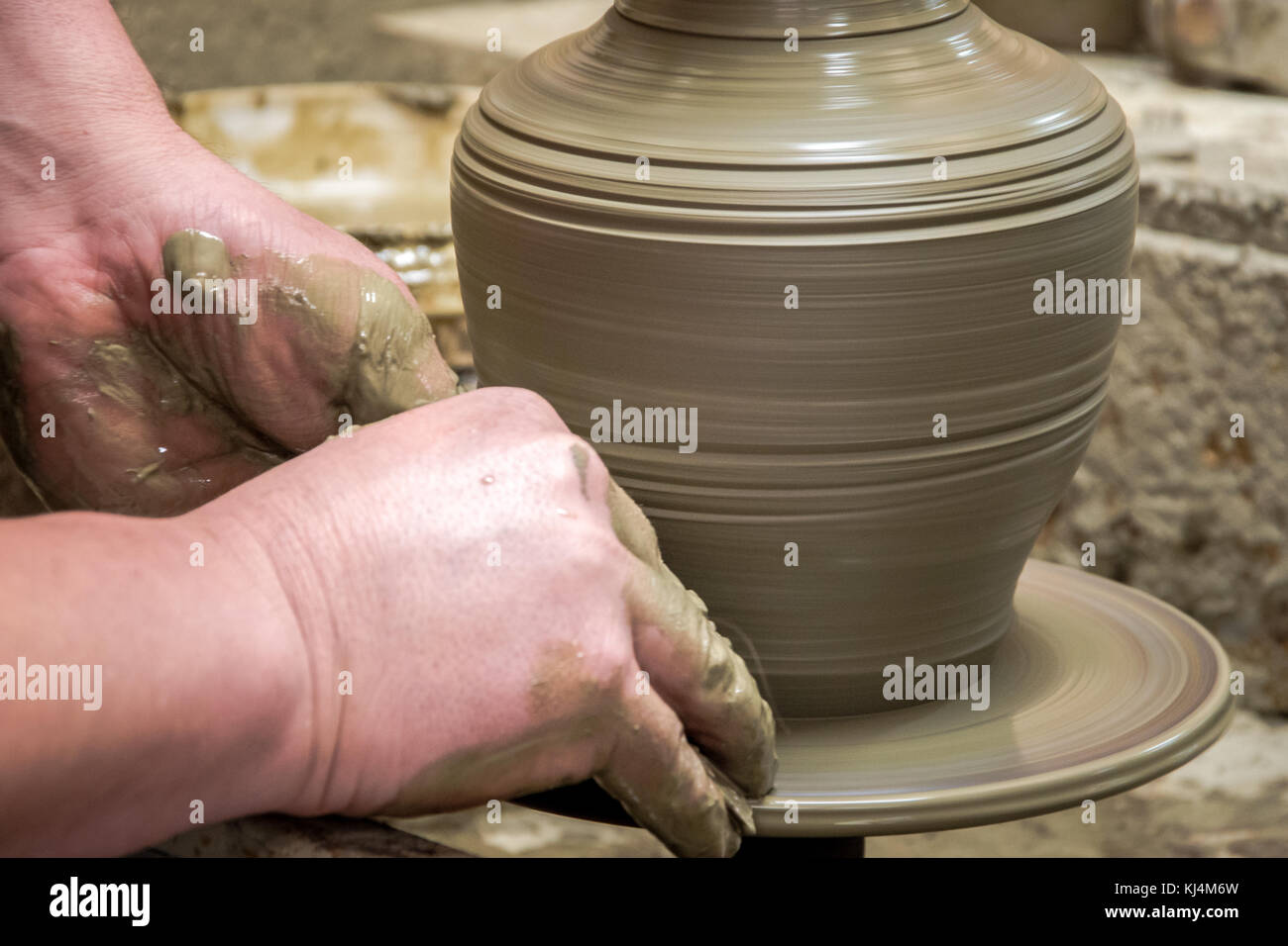 Man potter at work creating some traditional cups of white clay ...