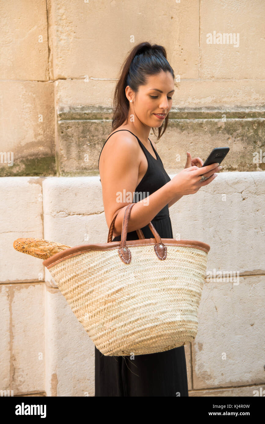 A woman is walking and texting while carrying a shopping bag Stock ...