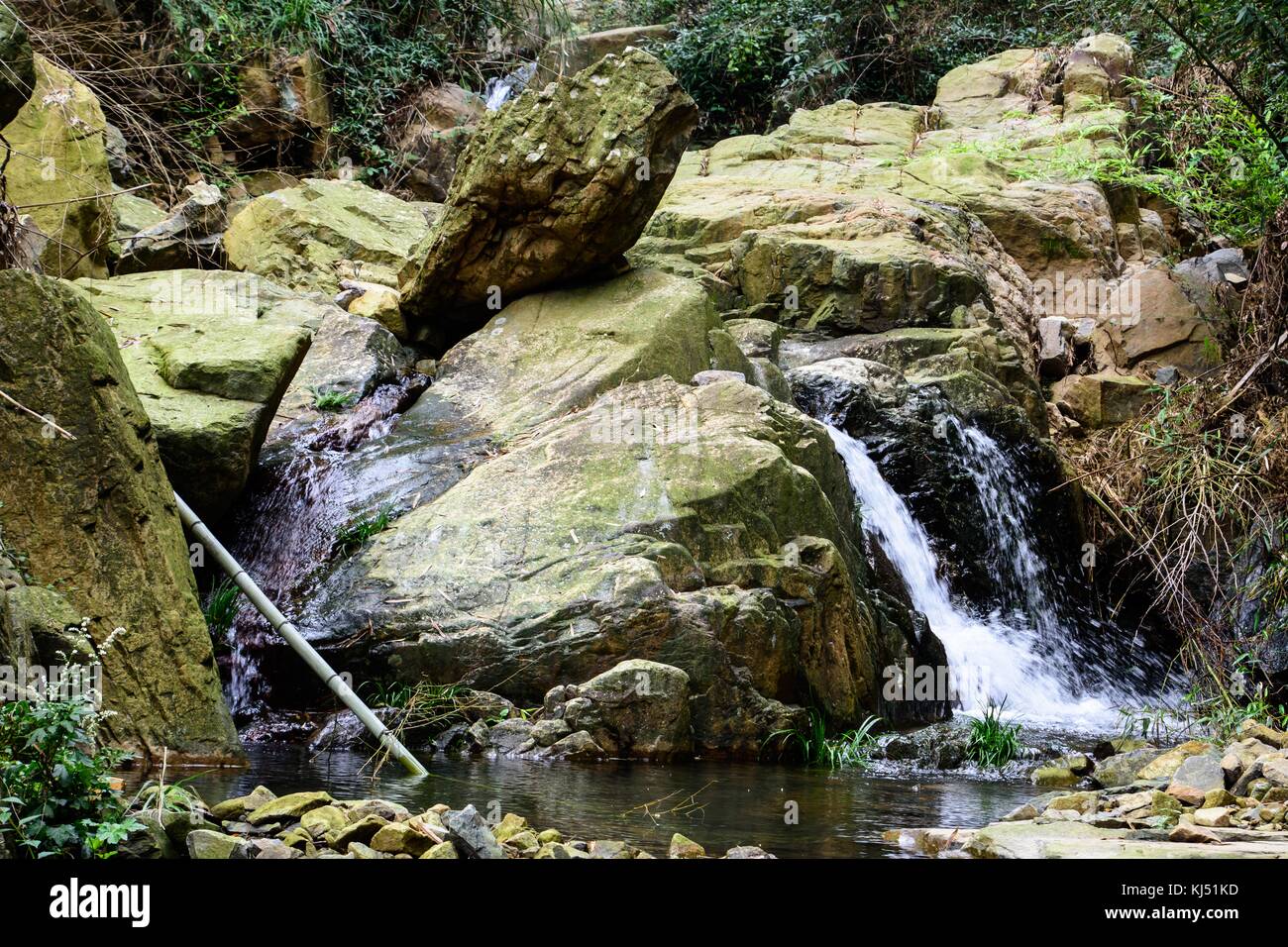 Water running down mountain stream forming a waterfall between rocks at ...