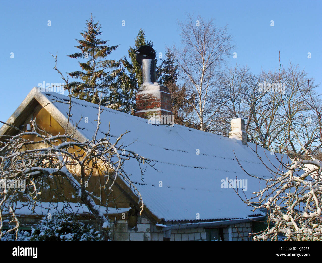 Chimneys on old country house roof are covered with ice and shining in ...