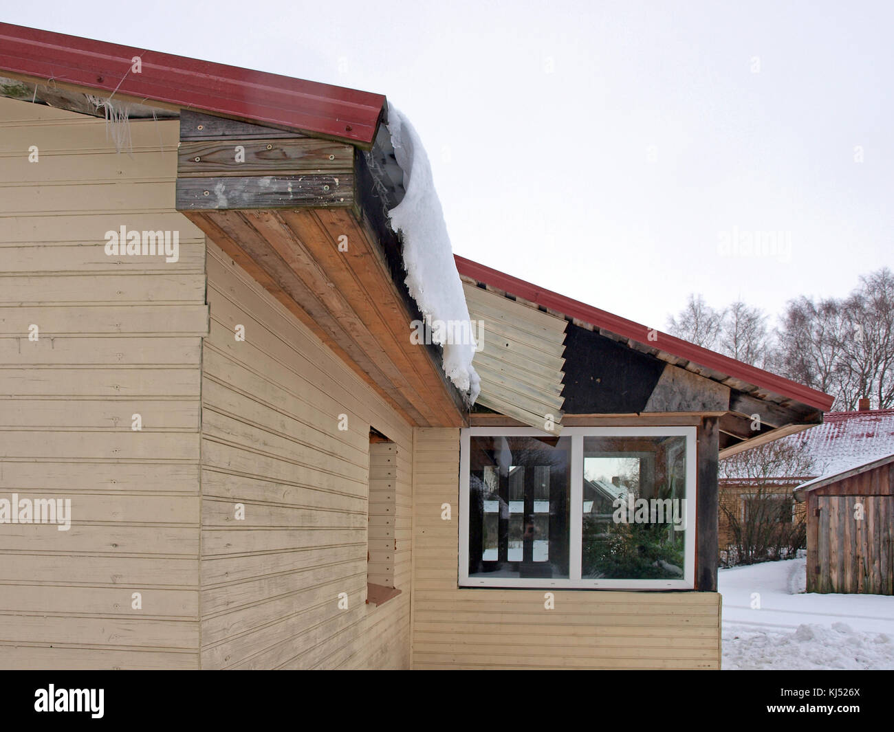 Wet melting snow slides down from metal house roof Stock Photo - Alamy