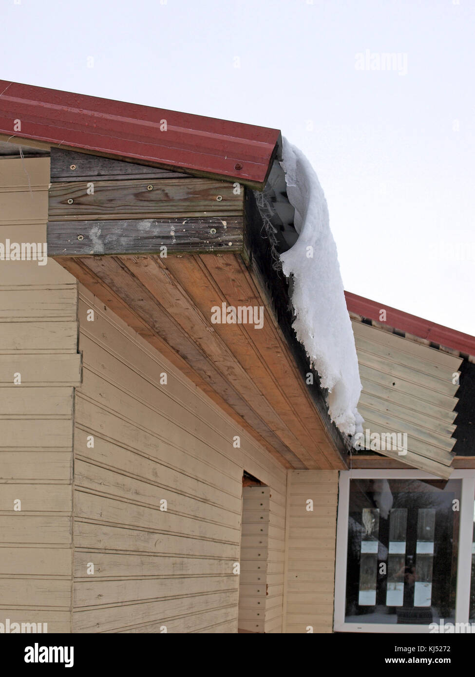 Wet melting snow slides down from metal house roof Stock Photo - Alamy