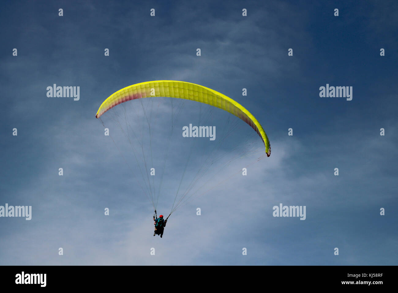 Paraglider flying in the blue sky against the background of clouds ...