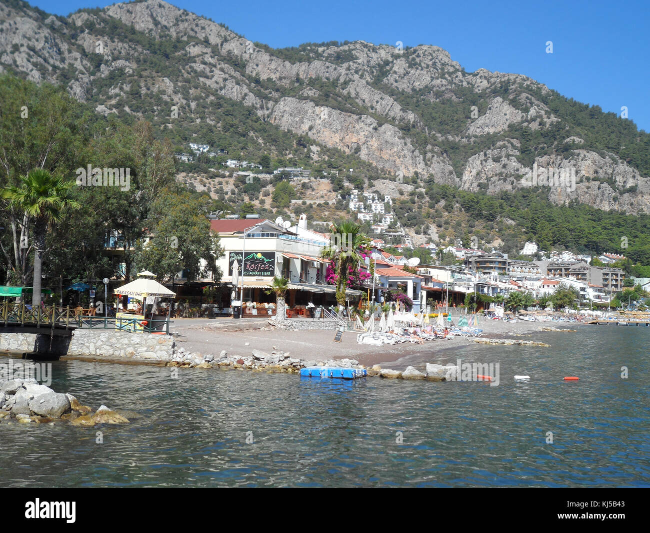 View of the public beach and promenade bars from the harbour, Turunc ...