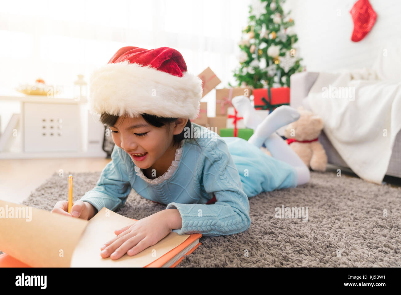 small child writes the letter to Santa lying down on the floor in the ...