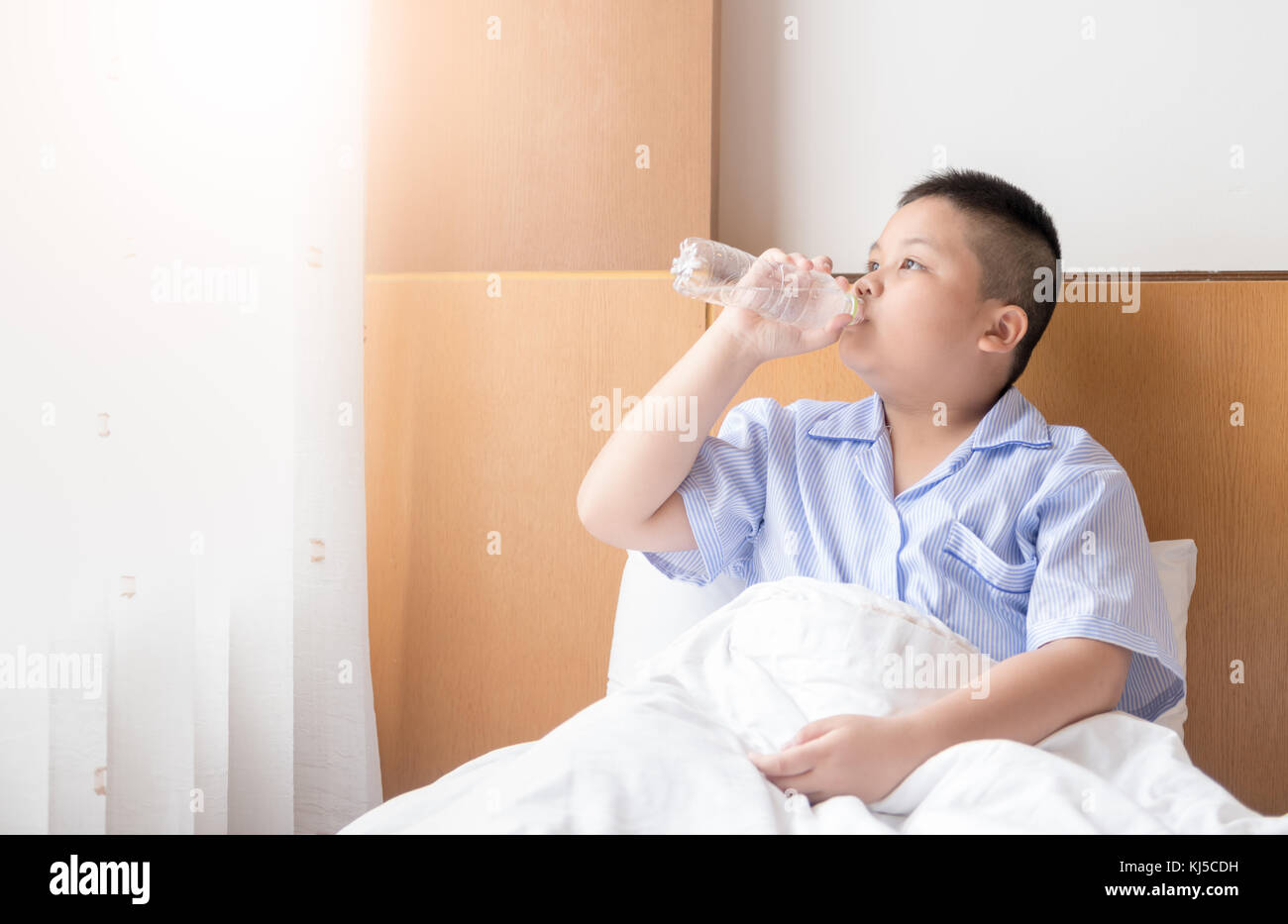 Obese fat boy drinking water on bed in morning after wake up, healthy ...