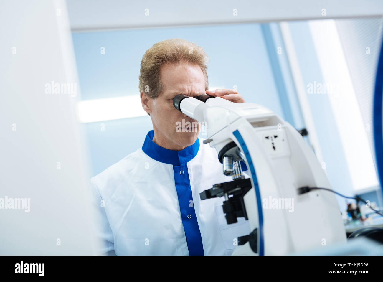 Serious scientist looking into a microscope Stock Photo - Alamy