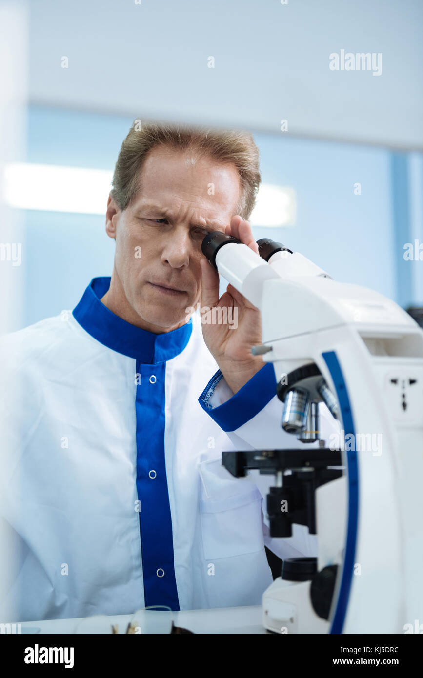 Concentrated scientist looking into a microscope Stock Photo - Alamy