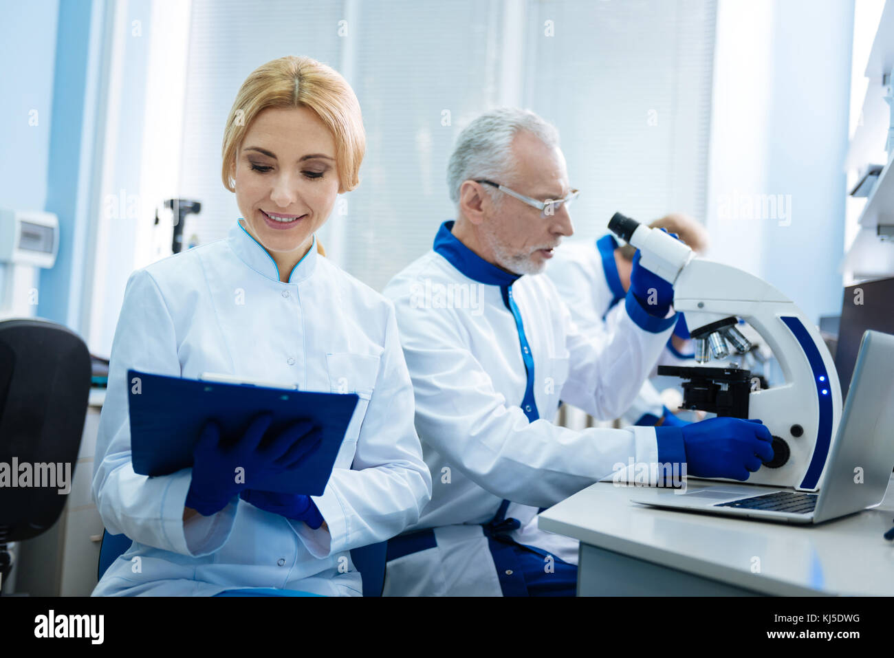 Smiling blond scientist working with other scientists Stock Photo - Alamy
