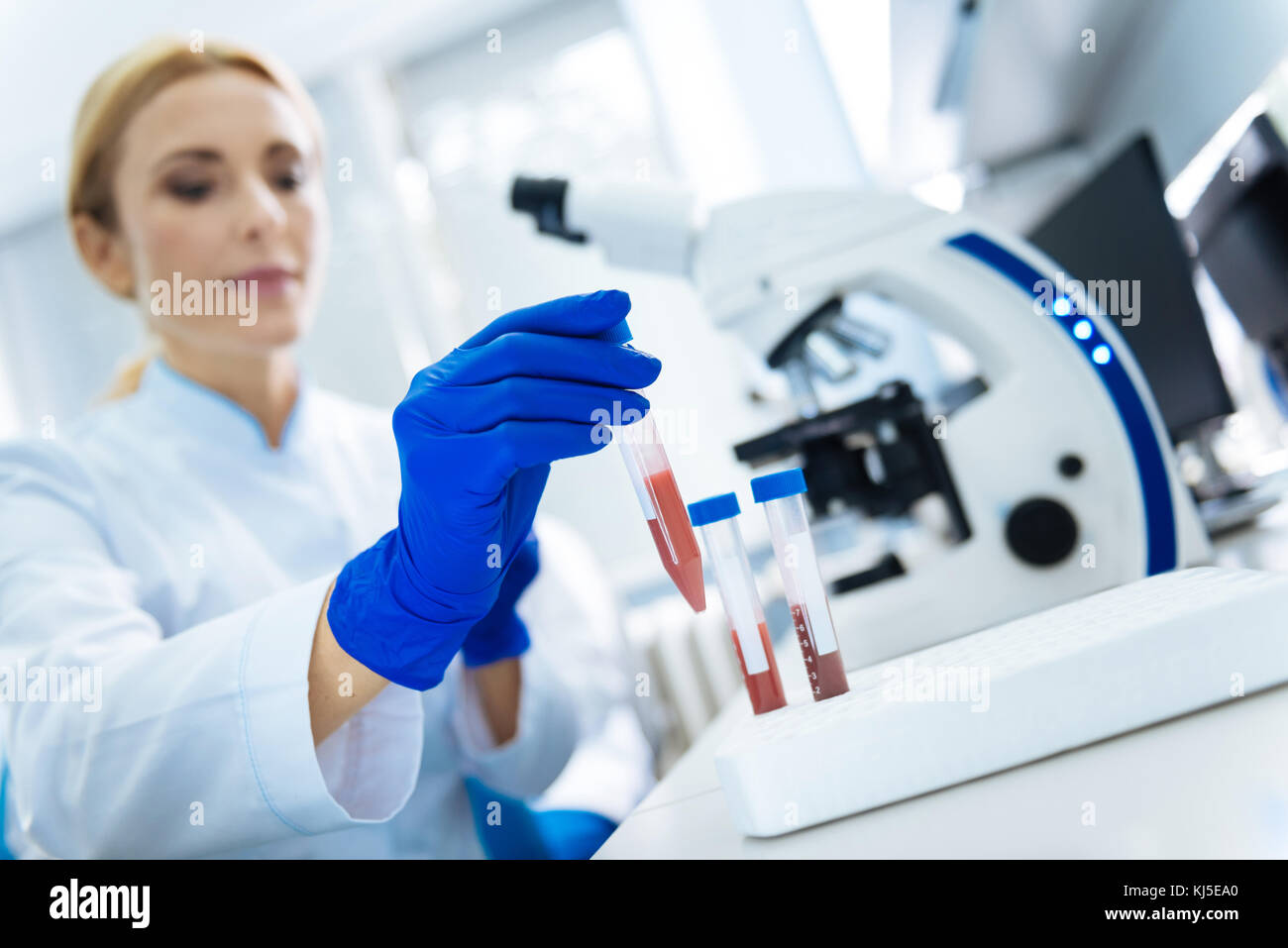 Alert scientist touching blood test tubes Stock Photo - Alamy
