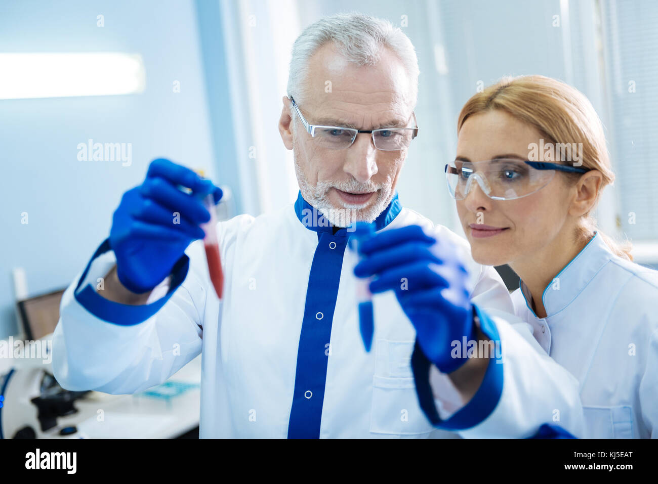 Happy researchers looking at test tubes Stock Photo - Alamy