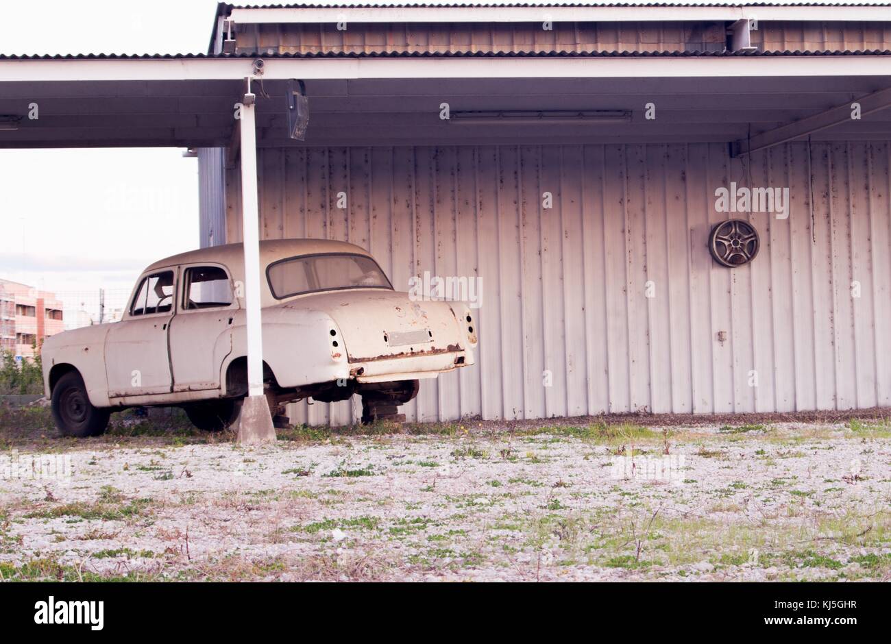 Old car without one of his wheels and hung rim of the wall Stock Photo ...