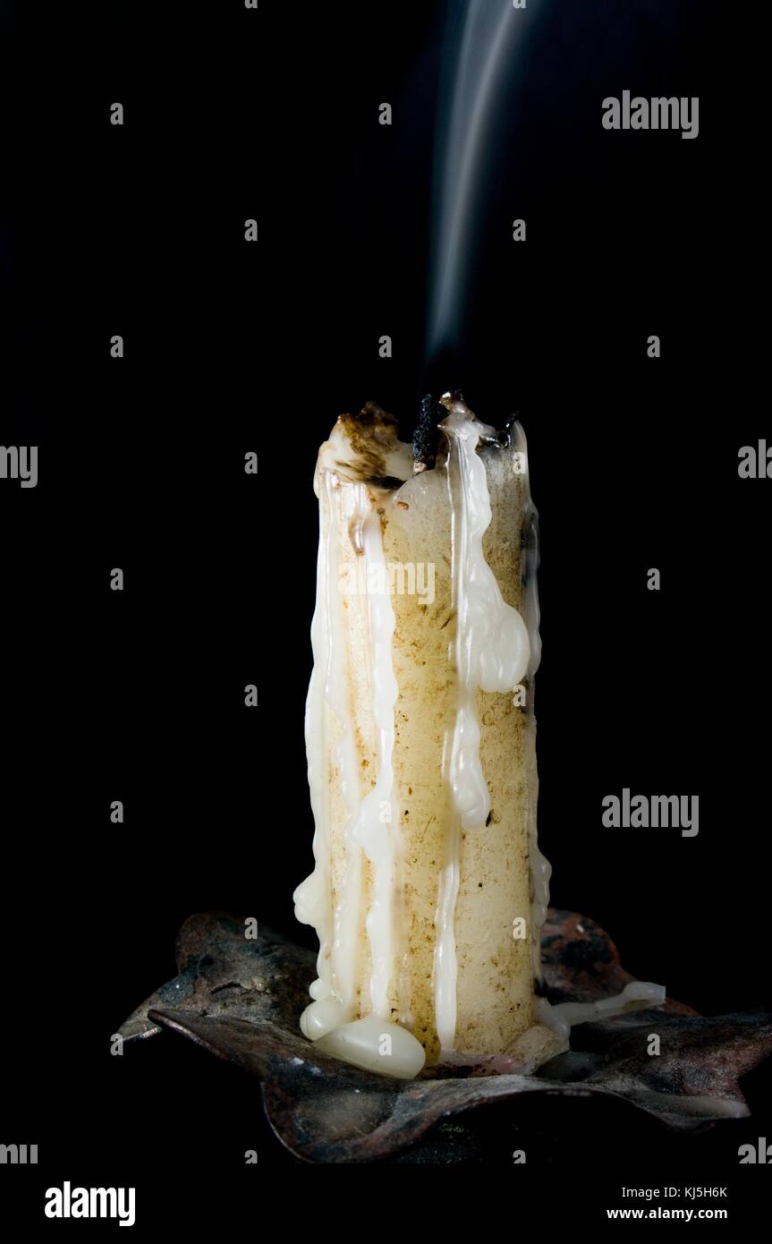 candle newly extinguished with smoke and the melted wax falling down in ...