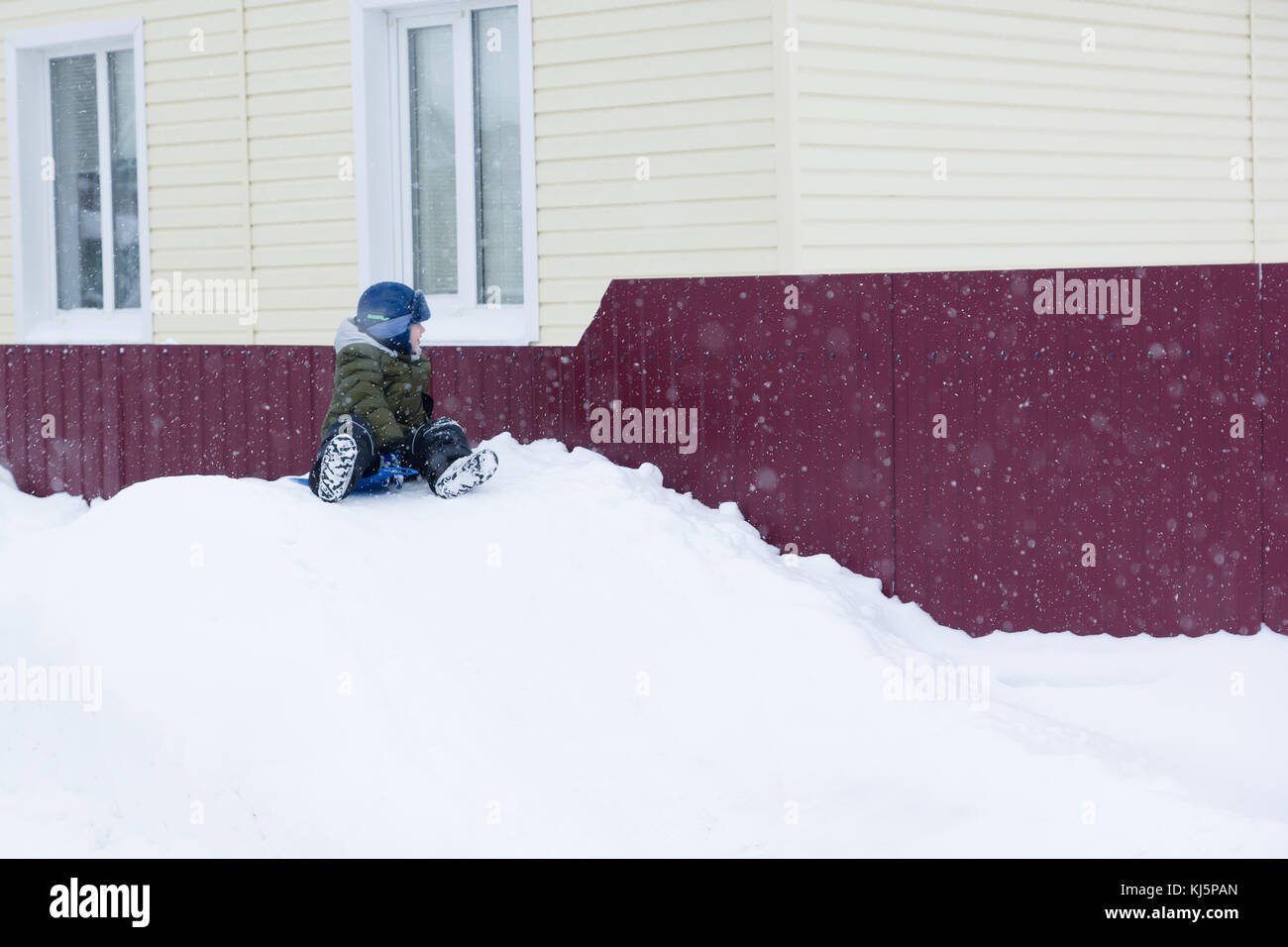 little boy in winter clothes sledding with snow slides Stock Photo - Alamy
