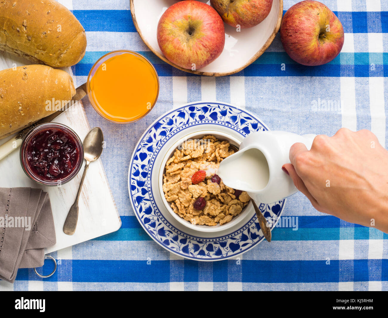 Home breakfast with cereals, milk, fruit and bread served on blue and ...