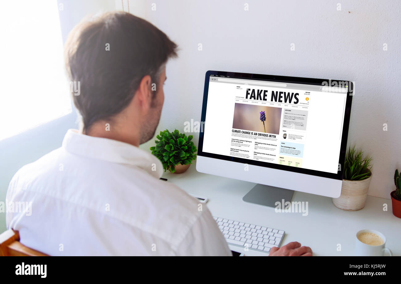 Man reading fake newson computer Stock Photo - Alamy