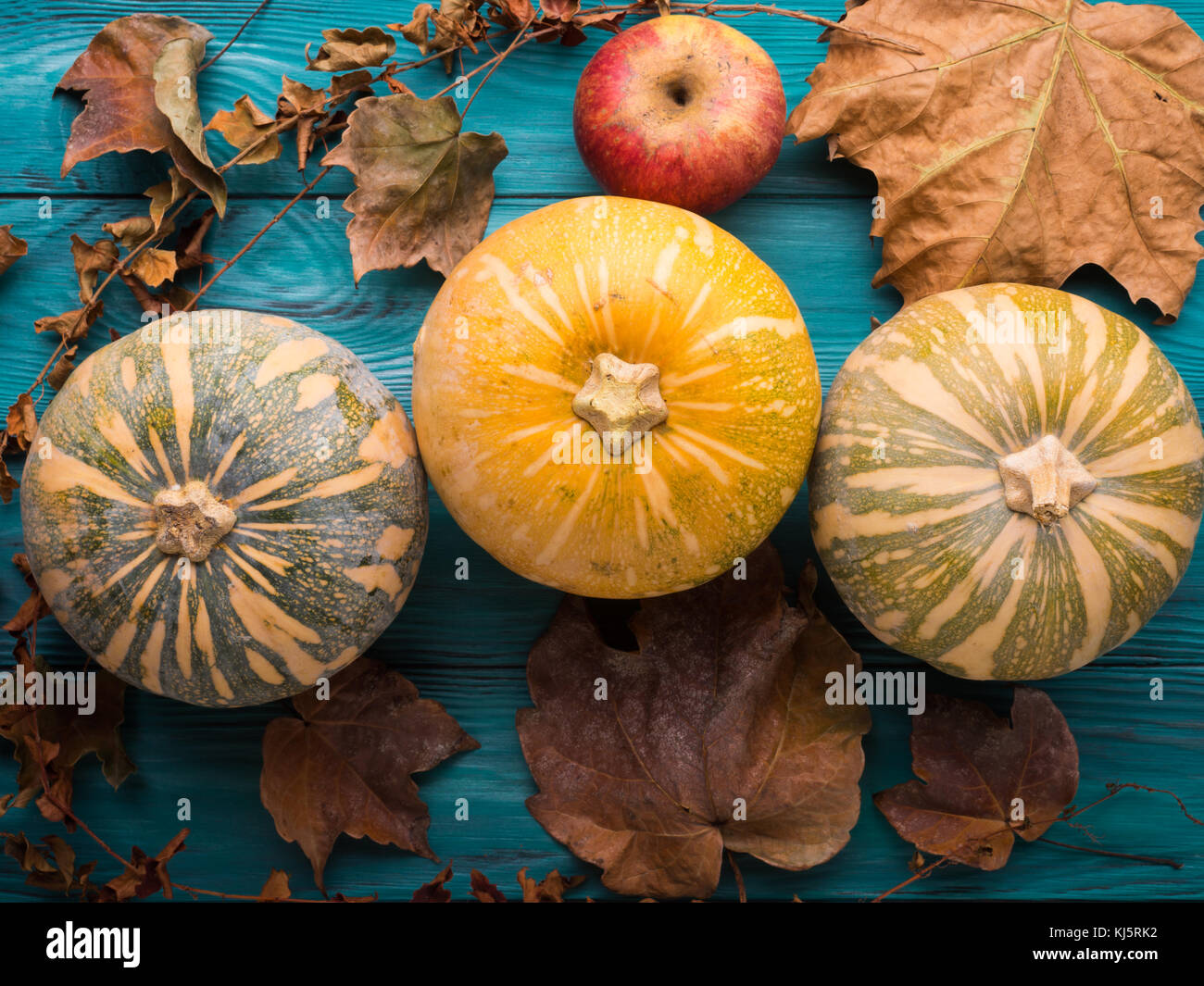 Moody green autumn background with pumpkins , apples, yellow leaves ...