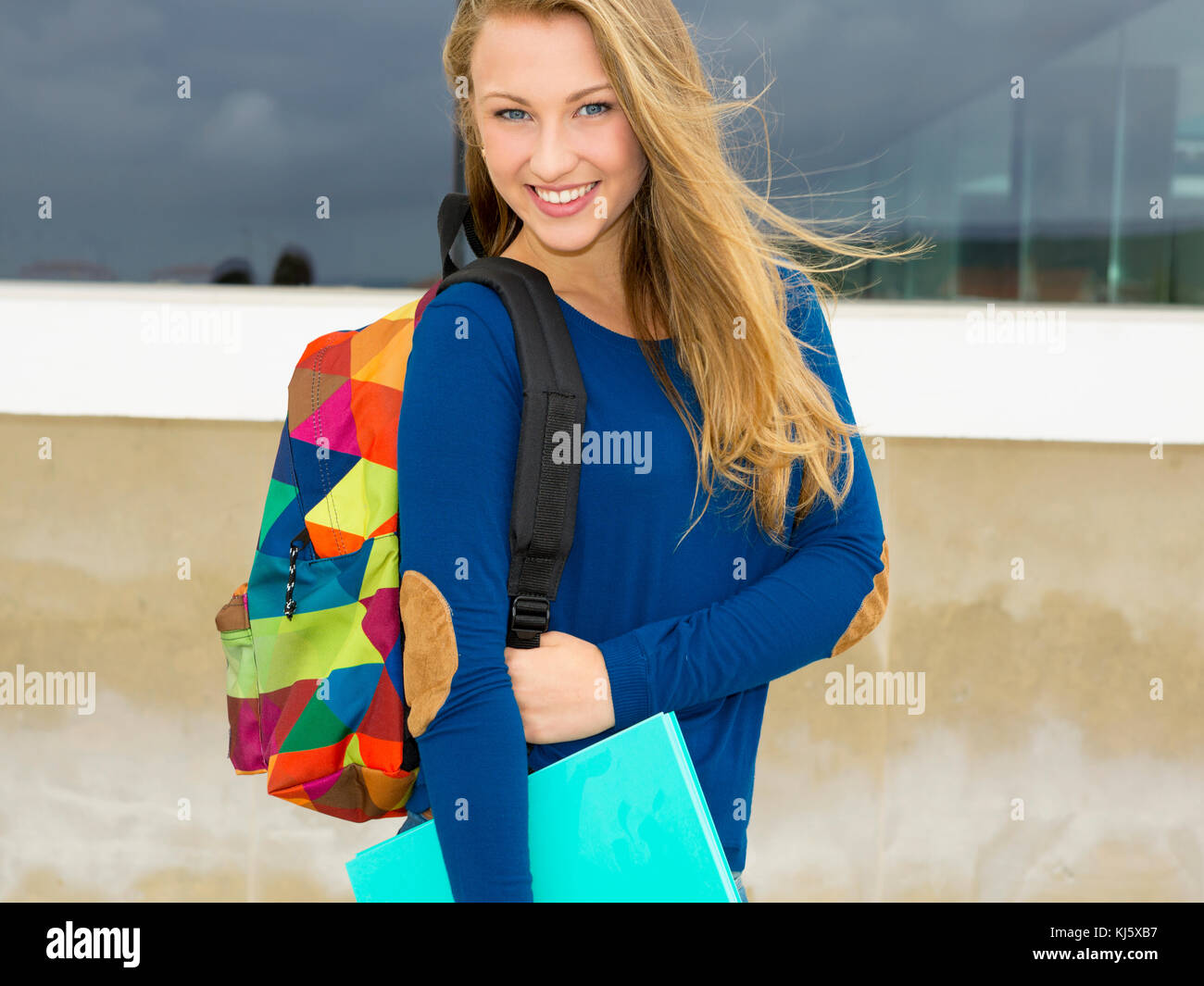 A beautiful student in the college holding a backpak and notebooks ...