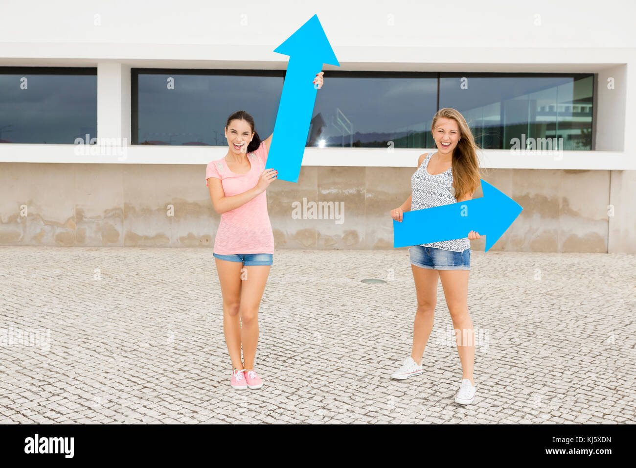 Teenage students holding blue arrows and pointing in diferent ...