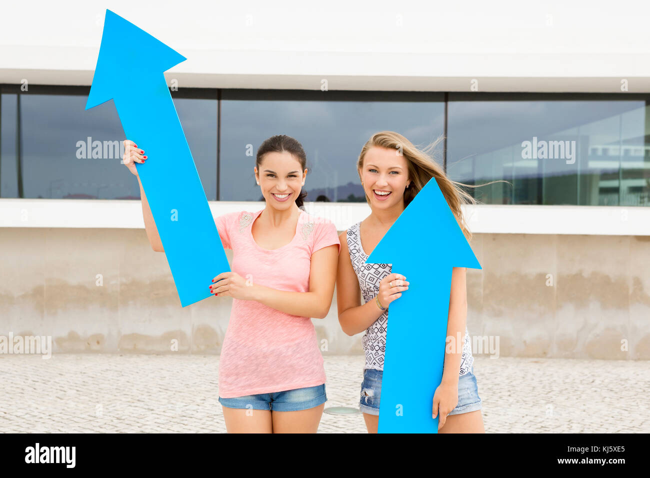 Teenage students holding blue arrows and pointing in diferent ...