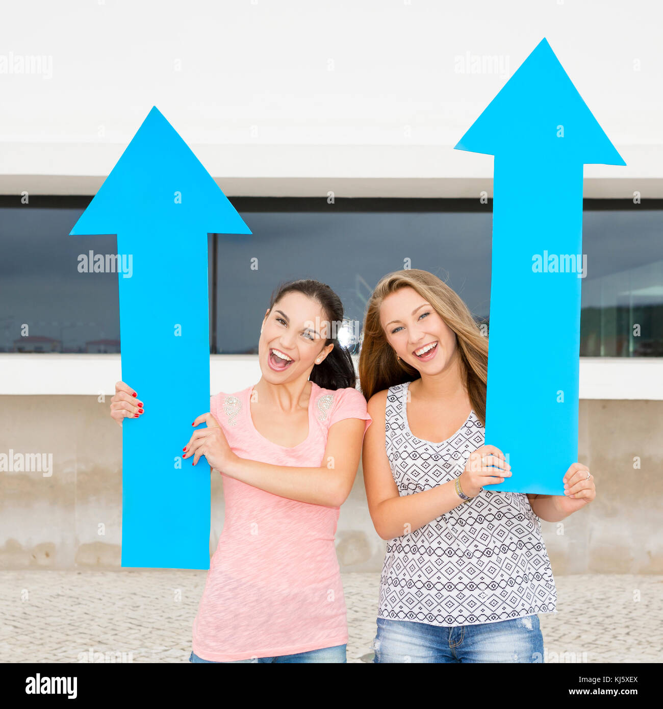 Teenage students holding blue arrows and pointing in diferent ...
